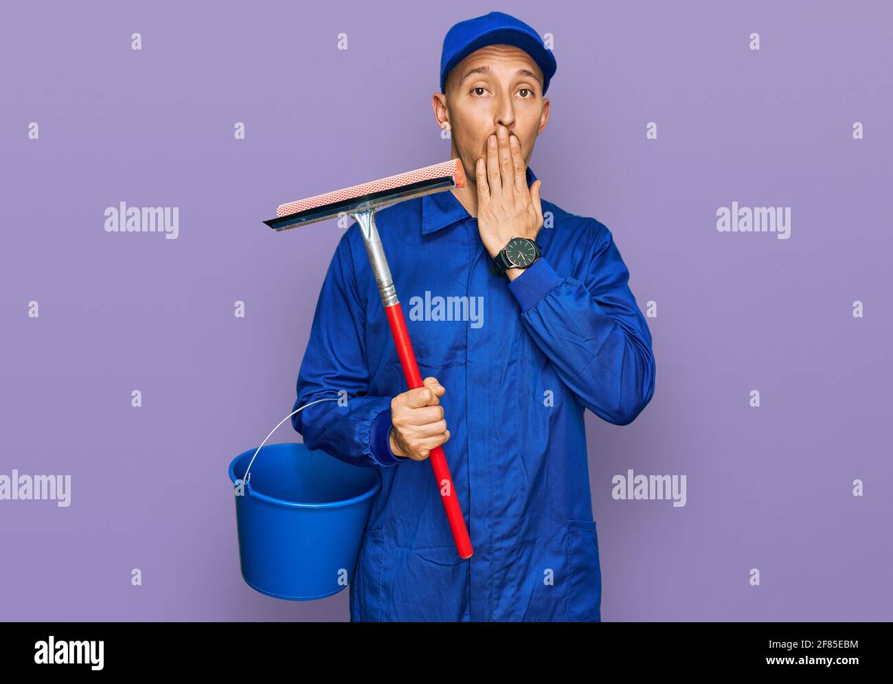 Bald man with beard wearing glass cleaner uniform and squeegee covering ...