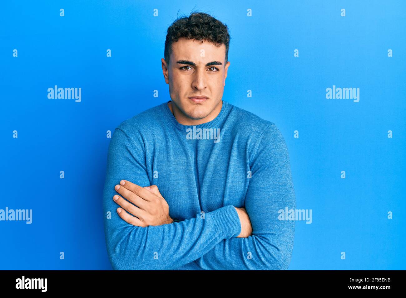 Hispanic young man wearing casual winter sweater shaking and freezing ...