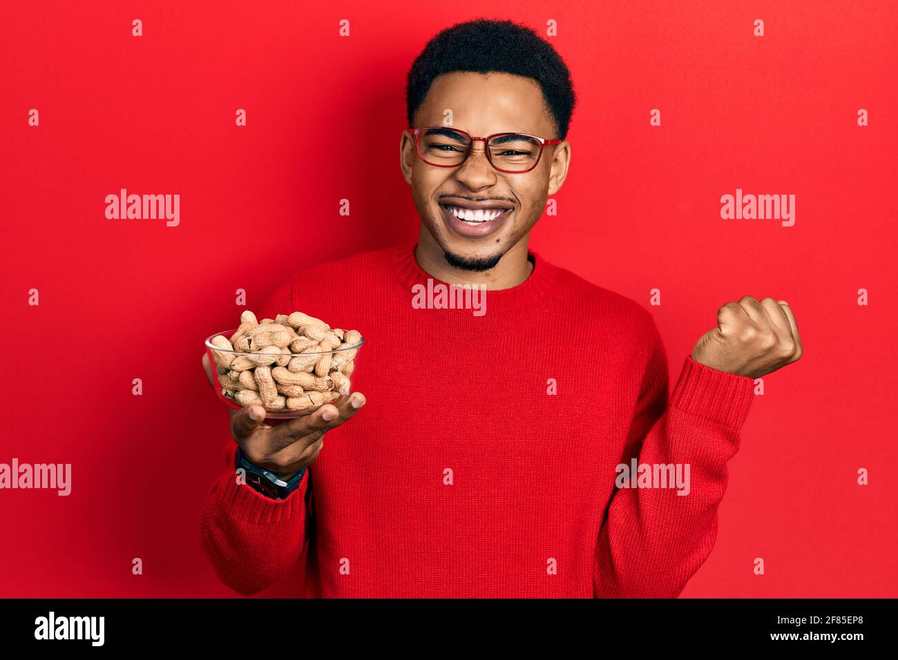 Young african american man holding peanuts screaming proud, celebrating ...