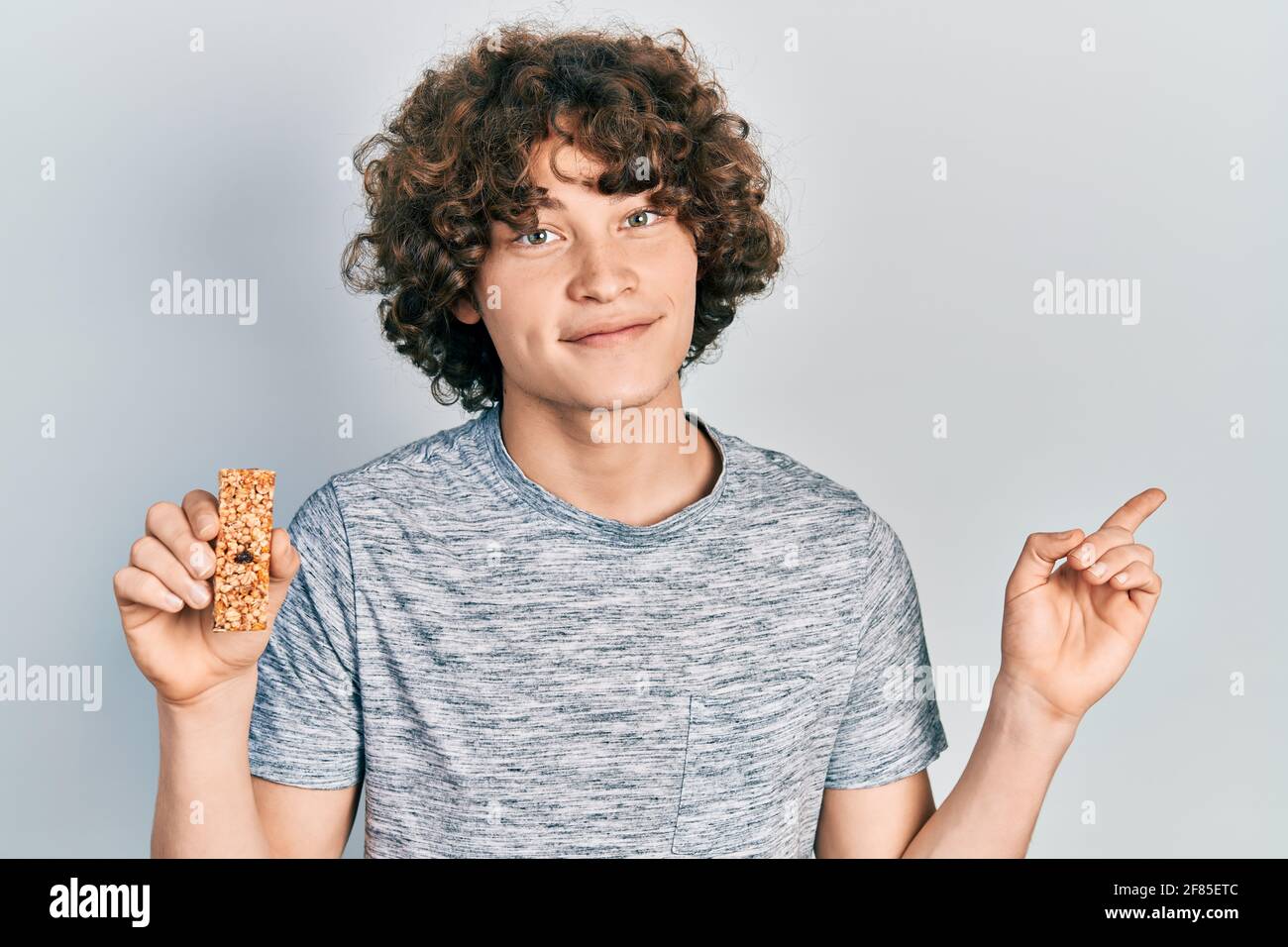 Handsome young man eating protein bar as healthy energy snack smiling ...