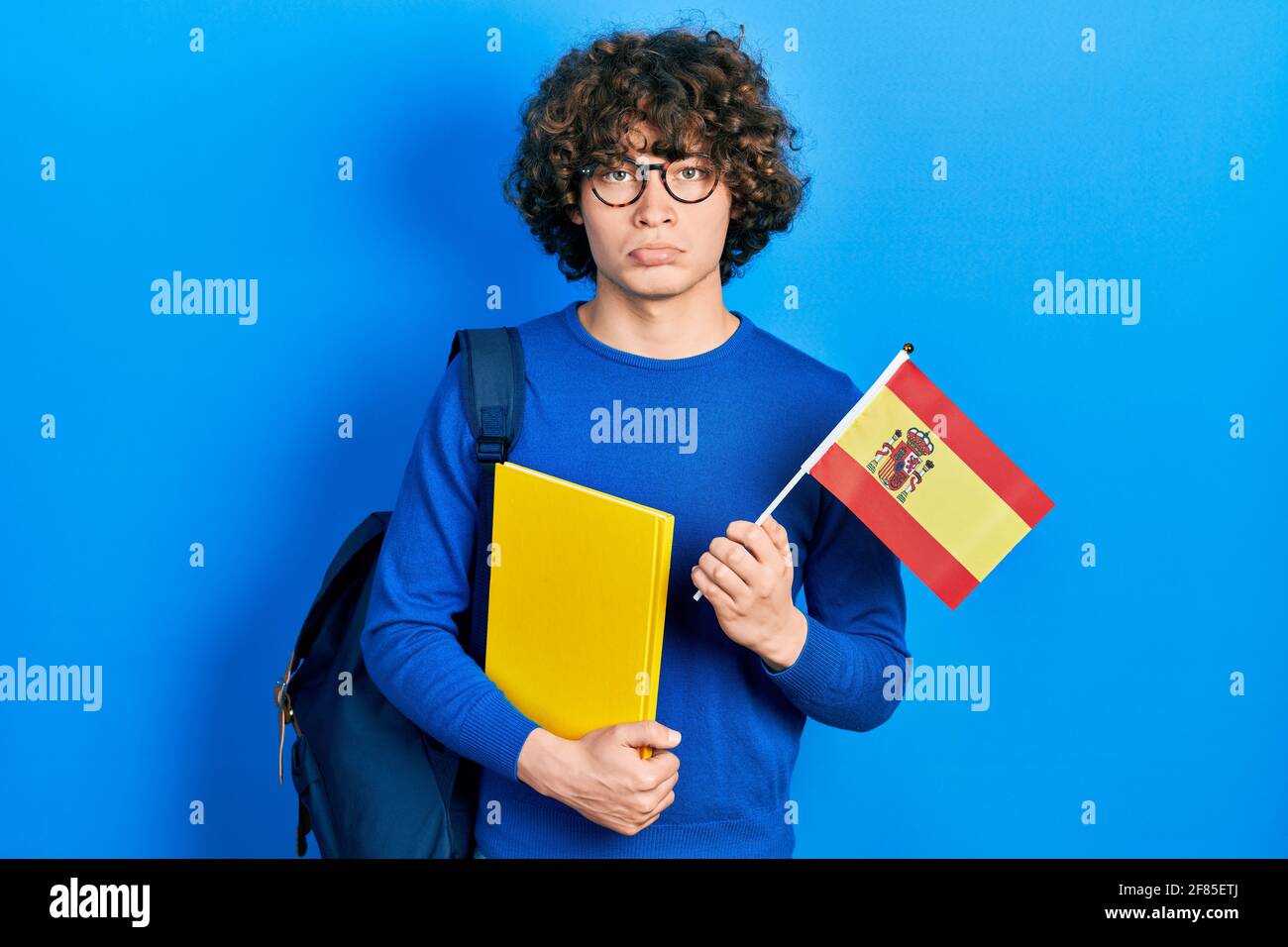 Handsome young man exchange student holding spanish flag depressed and ...