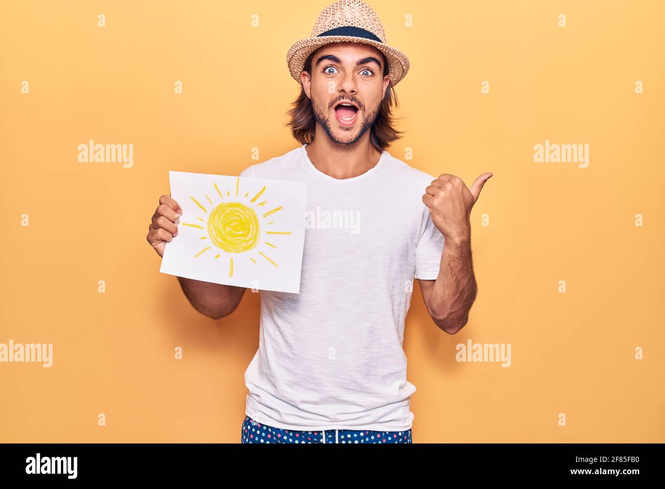 Young Handsome Man Holding Sun Draw Pointing Thumb Up To The Side