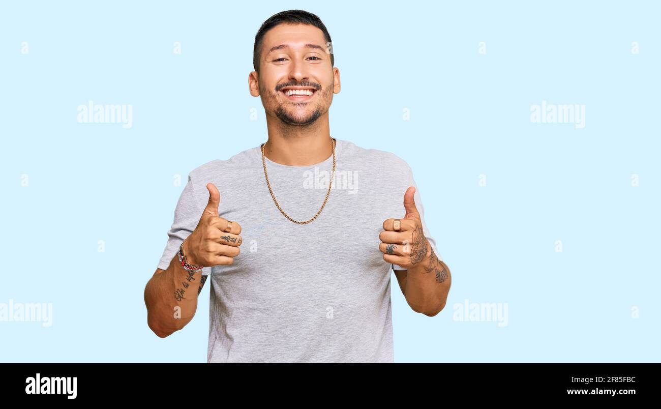 Handsome man with tattoos wearing 90s style success sign doing positive ...