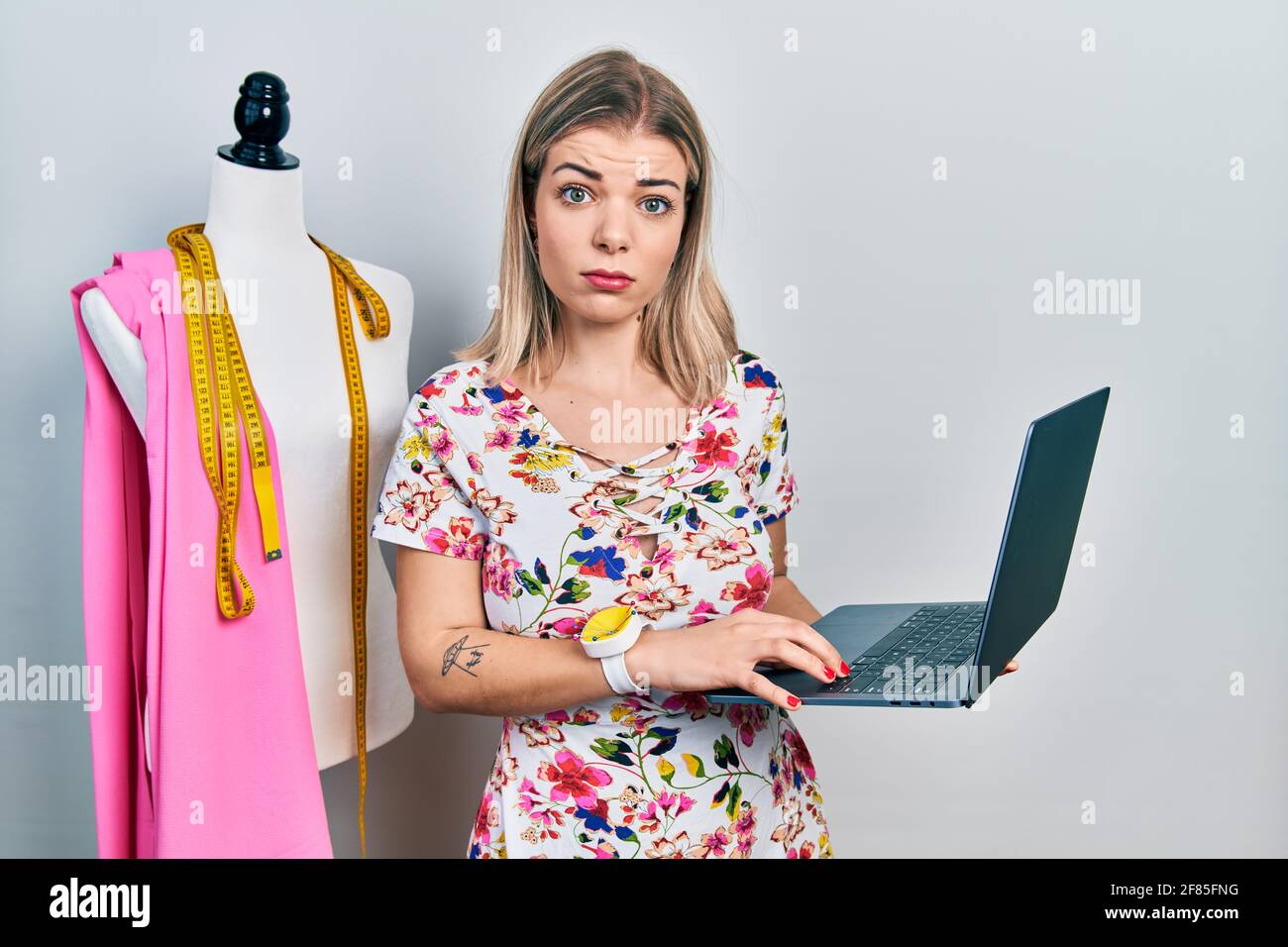 Beautiful caucasian woman dressmaker designer holding laptop clueless ...