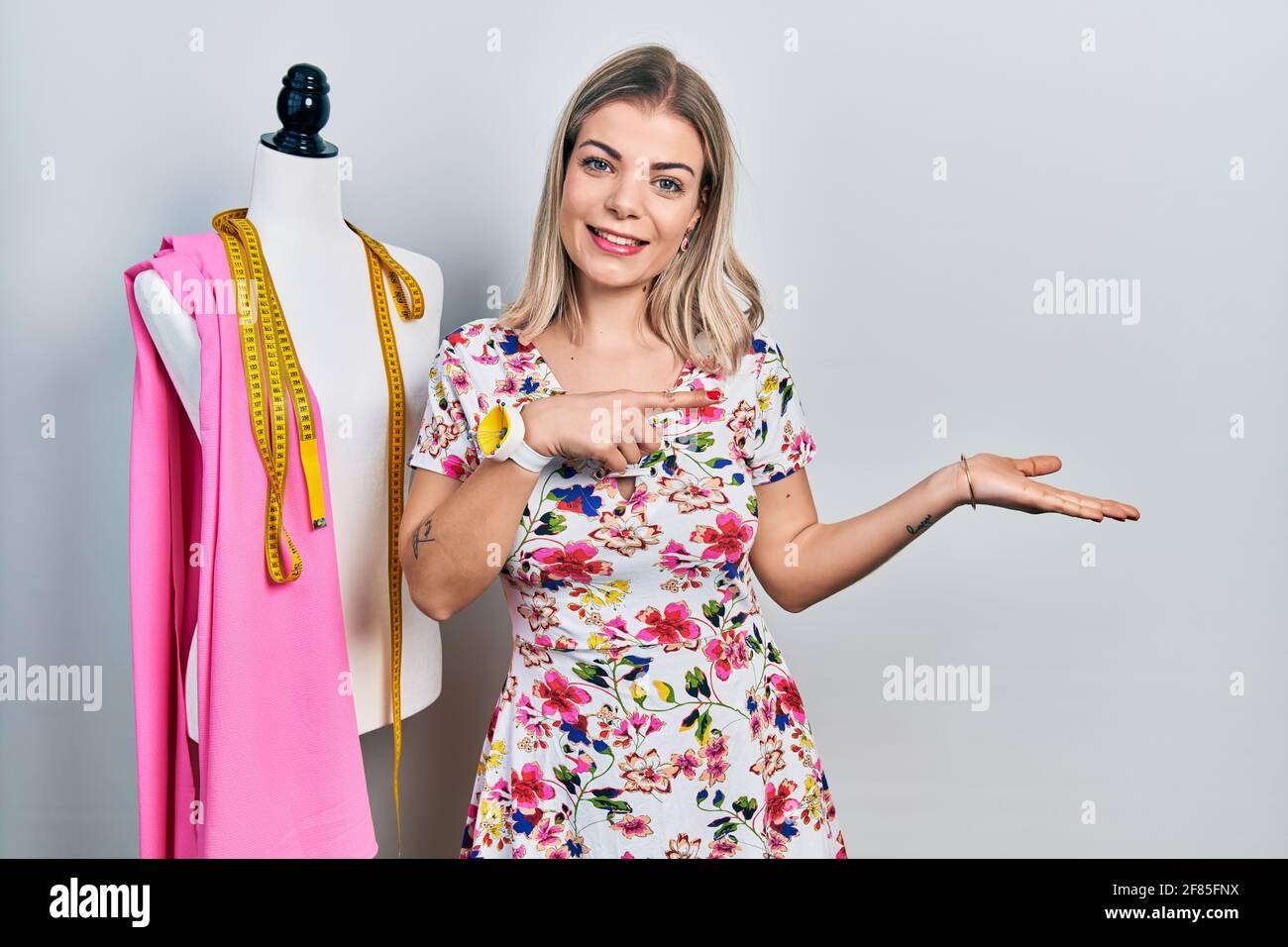 Beautiful caucasian woman dressmaker designer by manikin amazed and ...