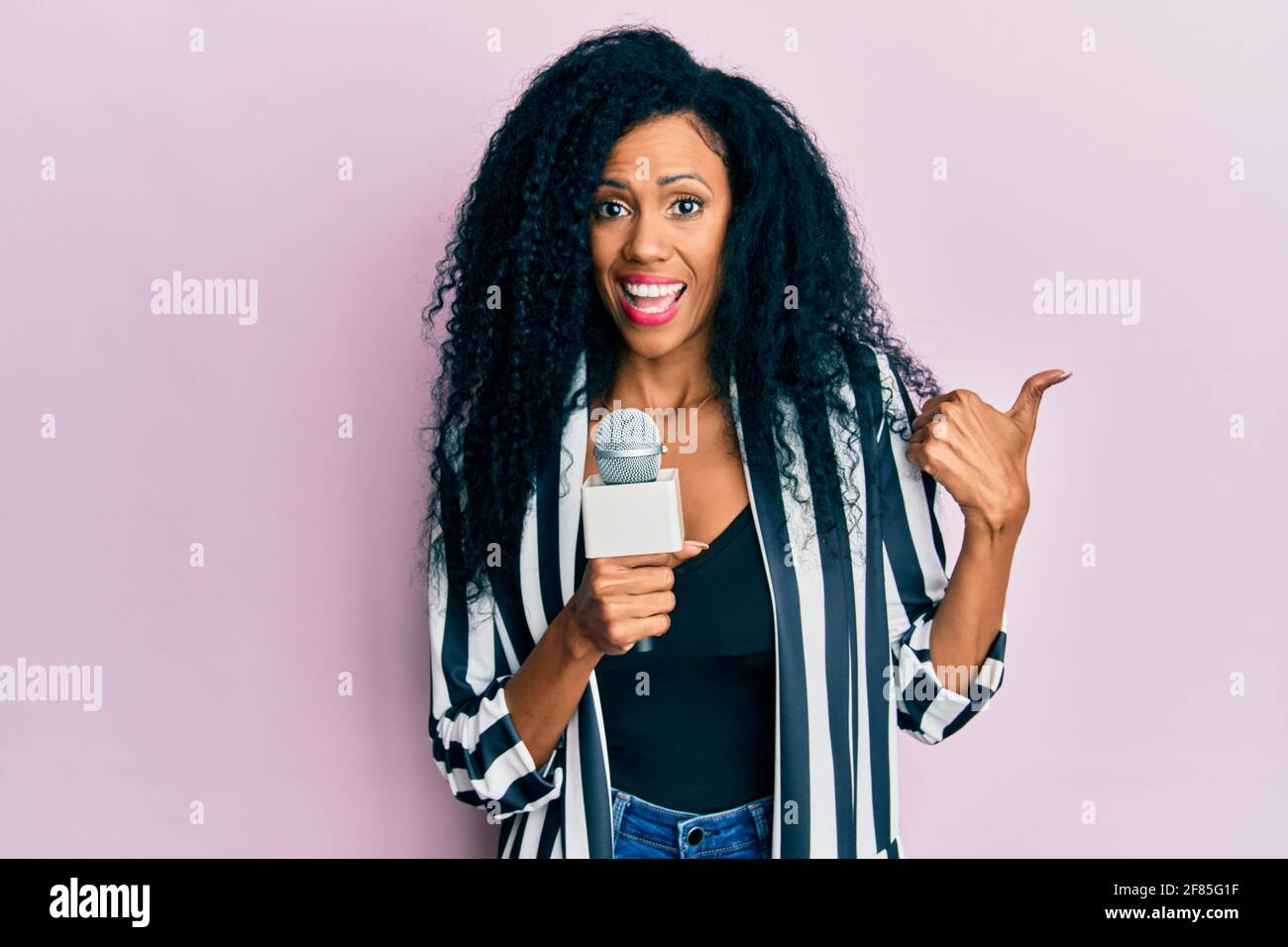 Middle age african american woman holding reporter microphone pointing ...