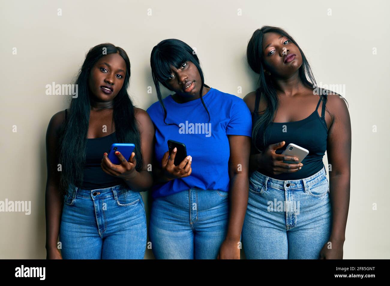 Three young african american friends using smartphone looking sleepy ...