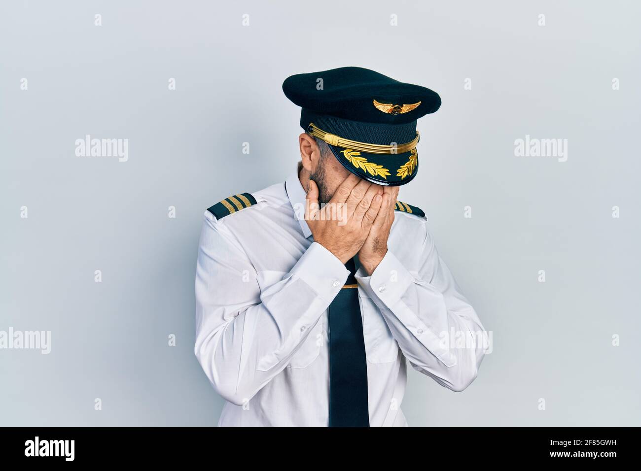 Young hispanic man wearing airplane pilot uniform with sad expression ...