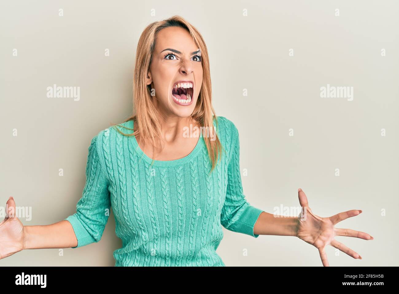 Beautiful blonde woman wearing casual winter sweater crazy and mad ...