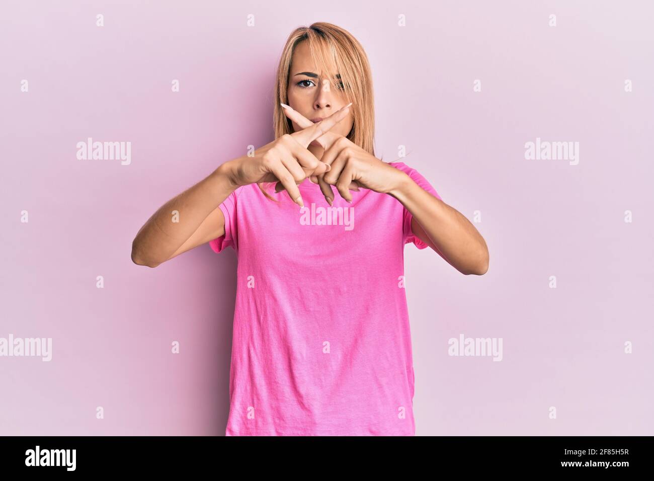 Beautiful blonde woman wearing casual pink tshirt rejection expression ...