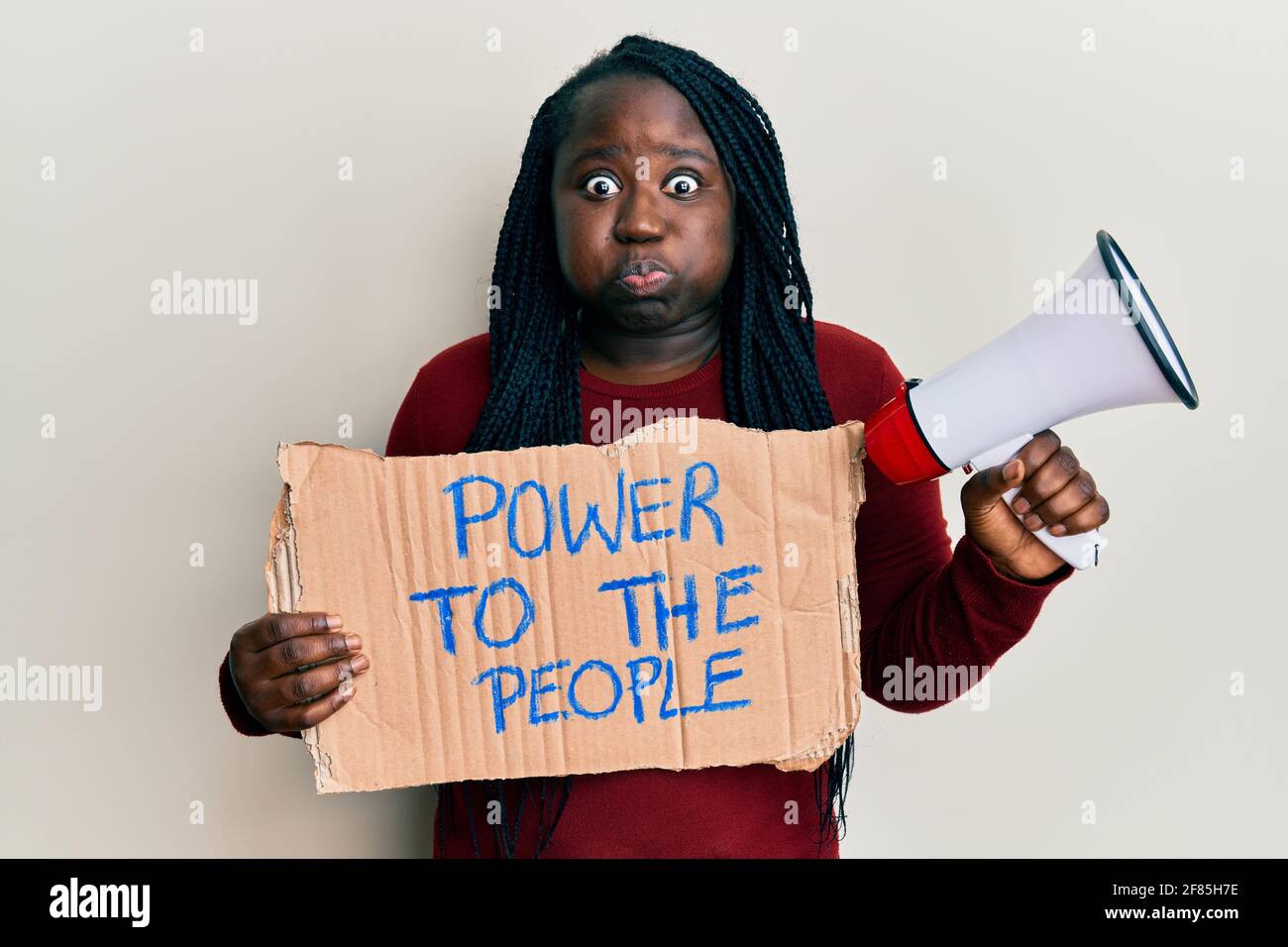 Young black woman with braids holding power to the people banner and ...