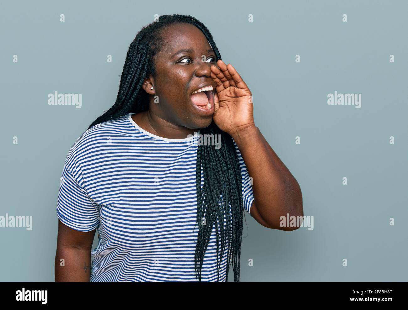 Young black woman with braids wearing casual clothes shouting and ...