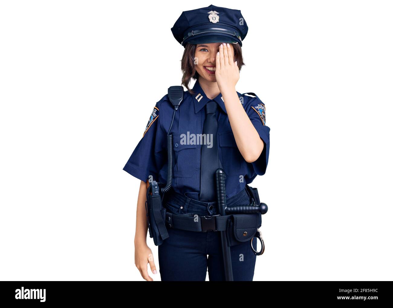 Young beautiful girl wearing police uniform covering one eye with hand ...