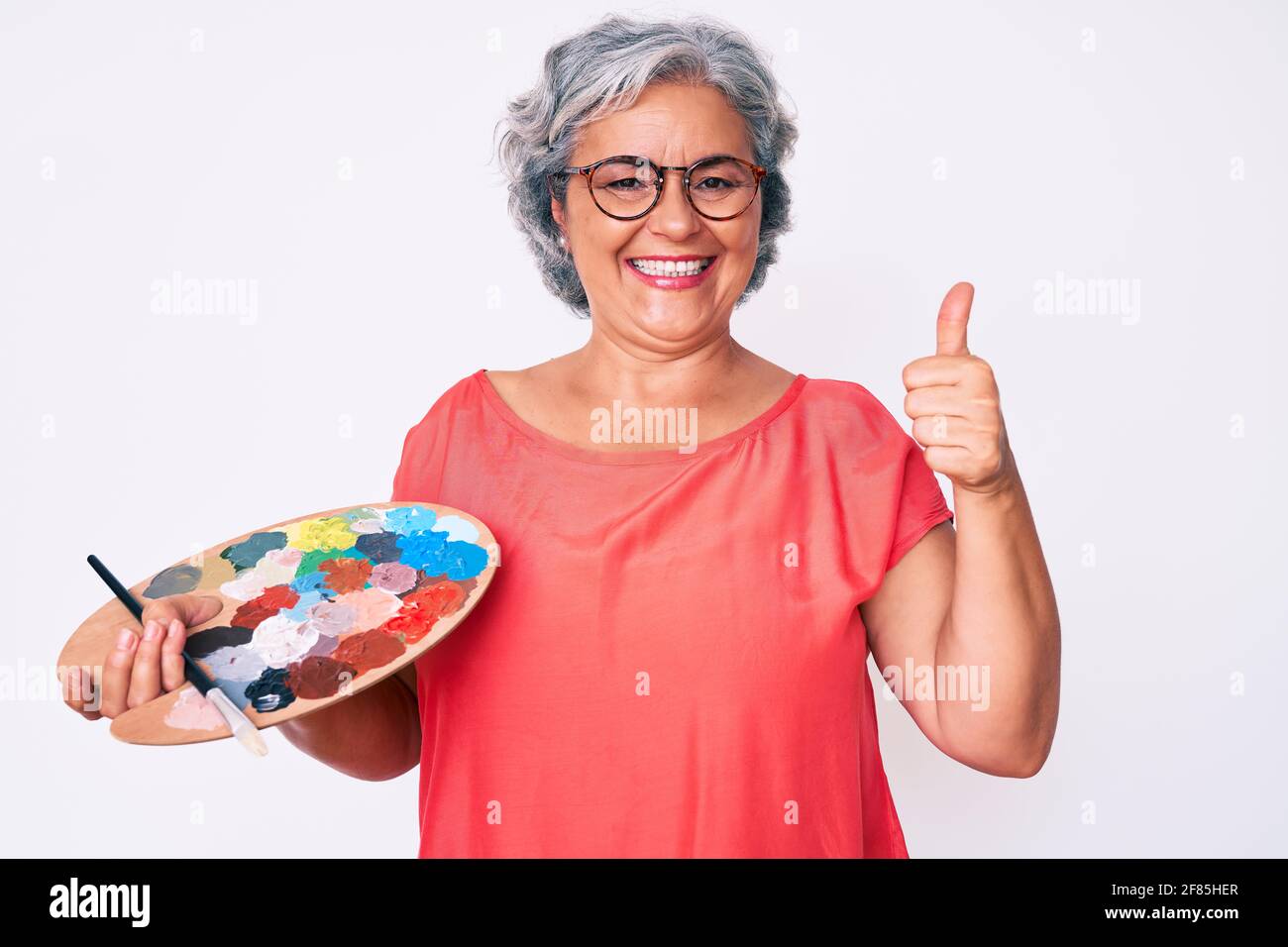 Senior hispanic grey- haired woman holding paintbrush and palette ...