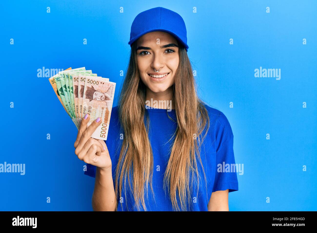 Young hispanic woman wearing delivery uniform and cap holding south ...