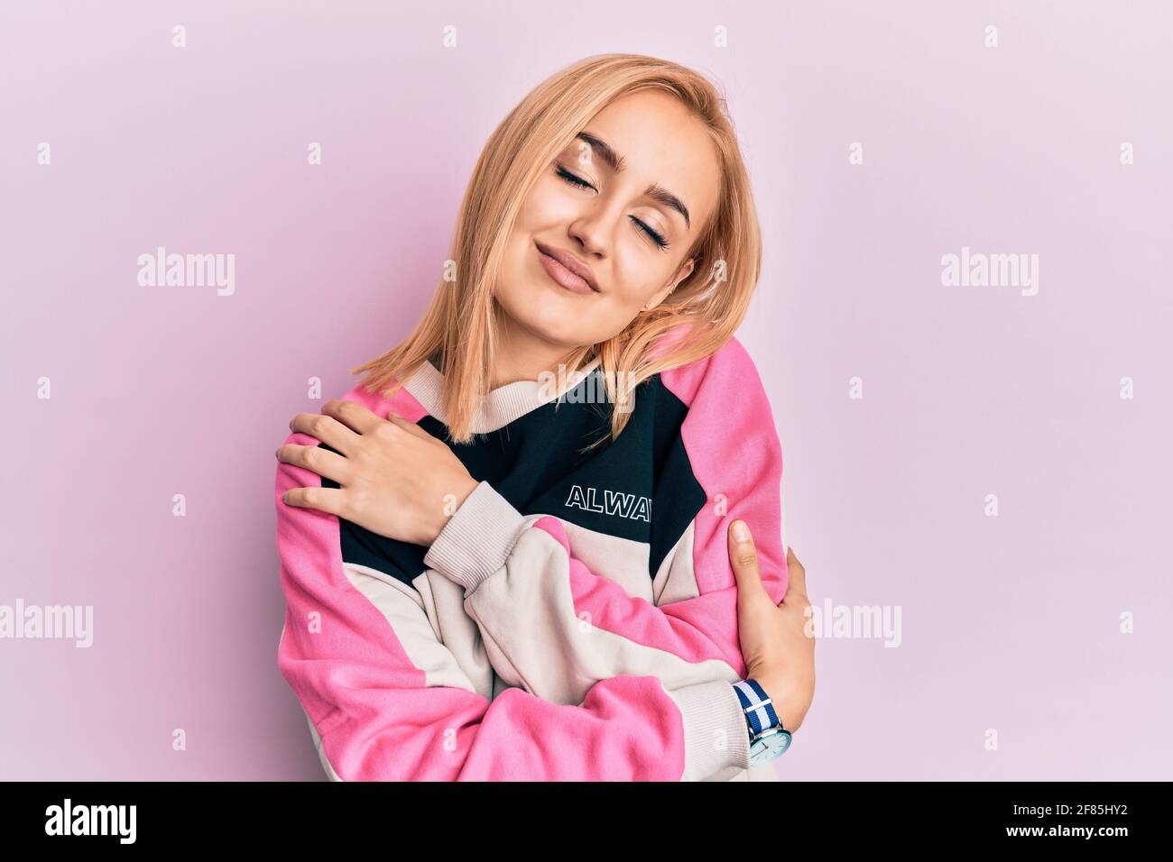 Beautiful caucasian woman wearing casual sporty jacket hugging oneself ...