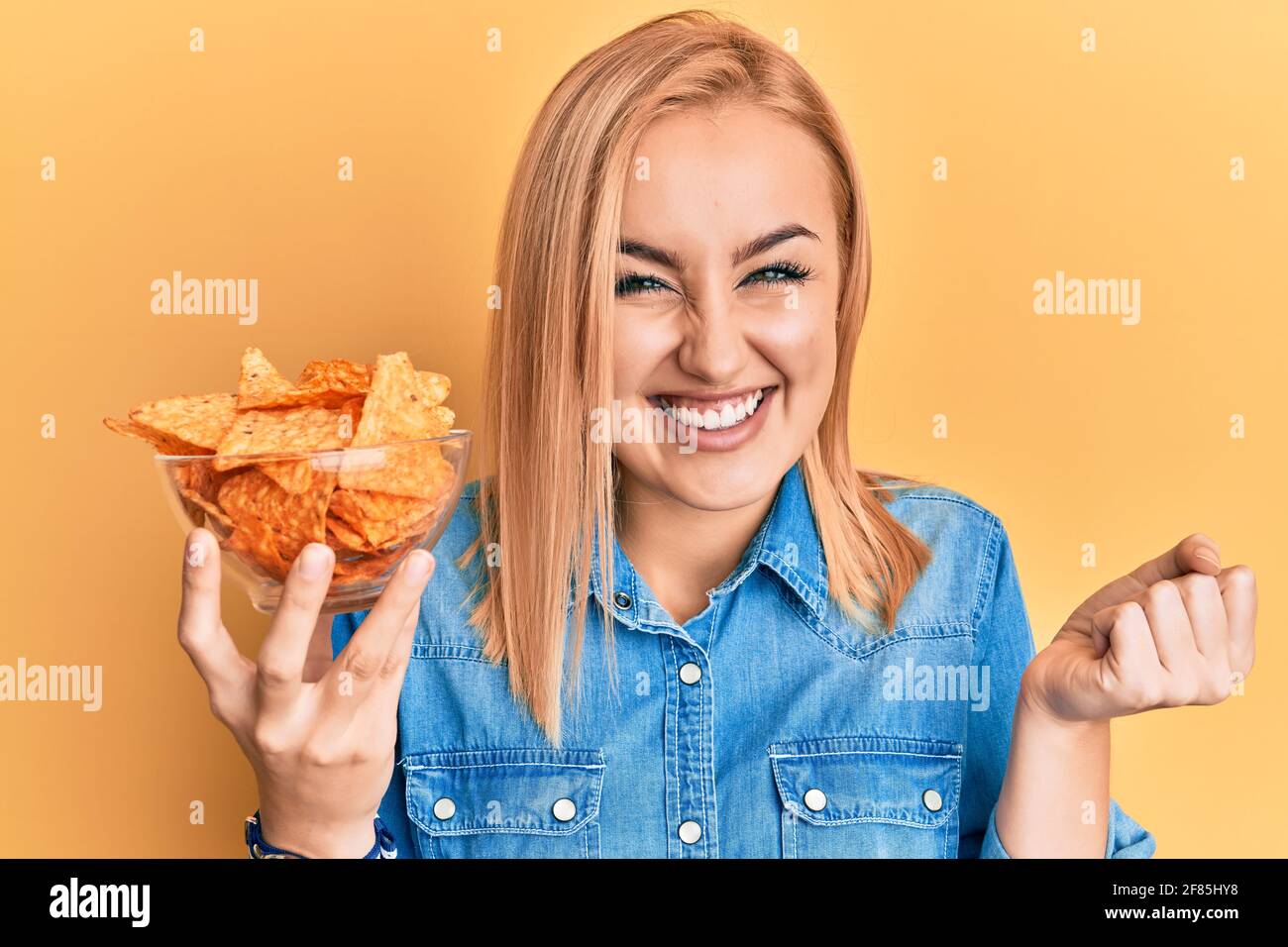Beautiful caucasian woman holding nachos potato chips screaming proud ...