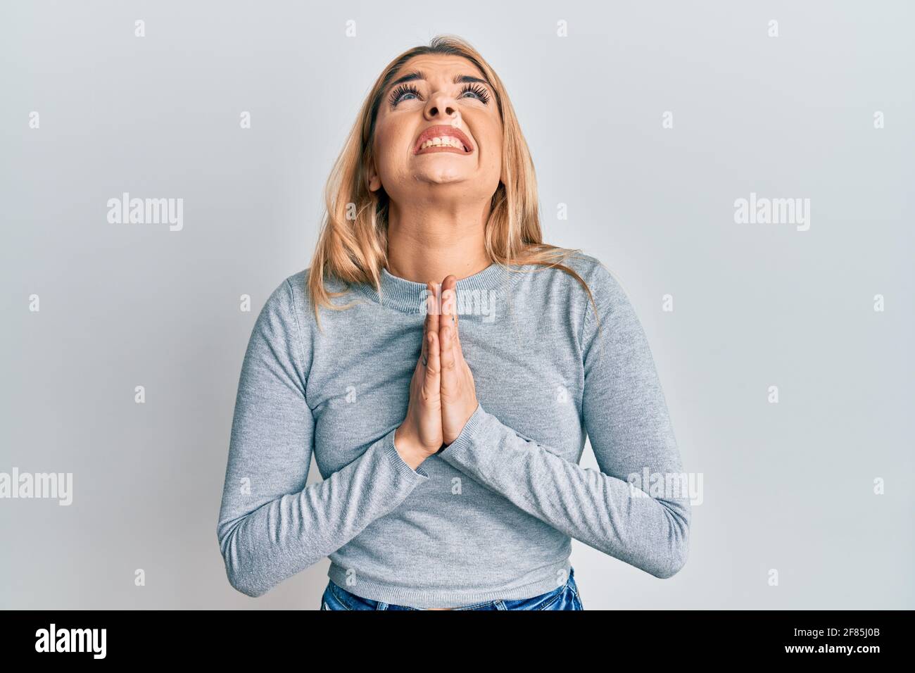 Young caucasian woman wearing casual clothes begging and praying with ...