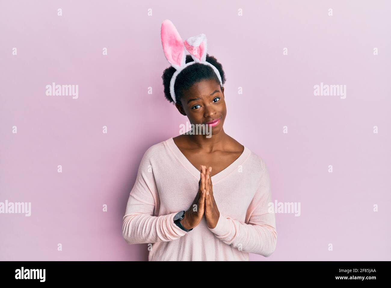 Young african american girl wearing cute easter bunny ears praying with ...