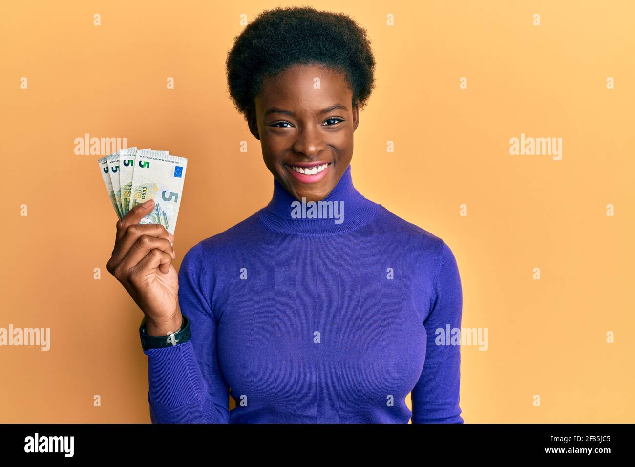 Young african american girl holding bunch of 5 euro banknotes looking ...
