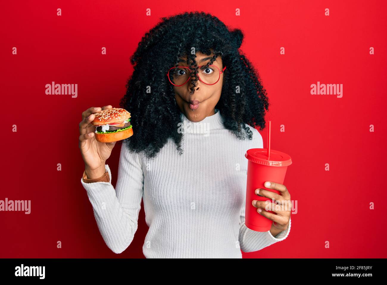 African american woman with afro hair eating a tasty classic burger and ...