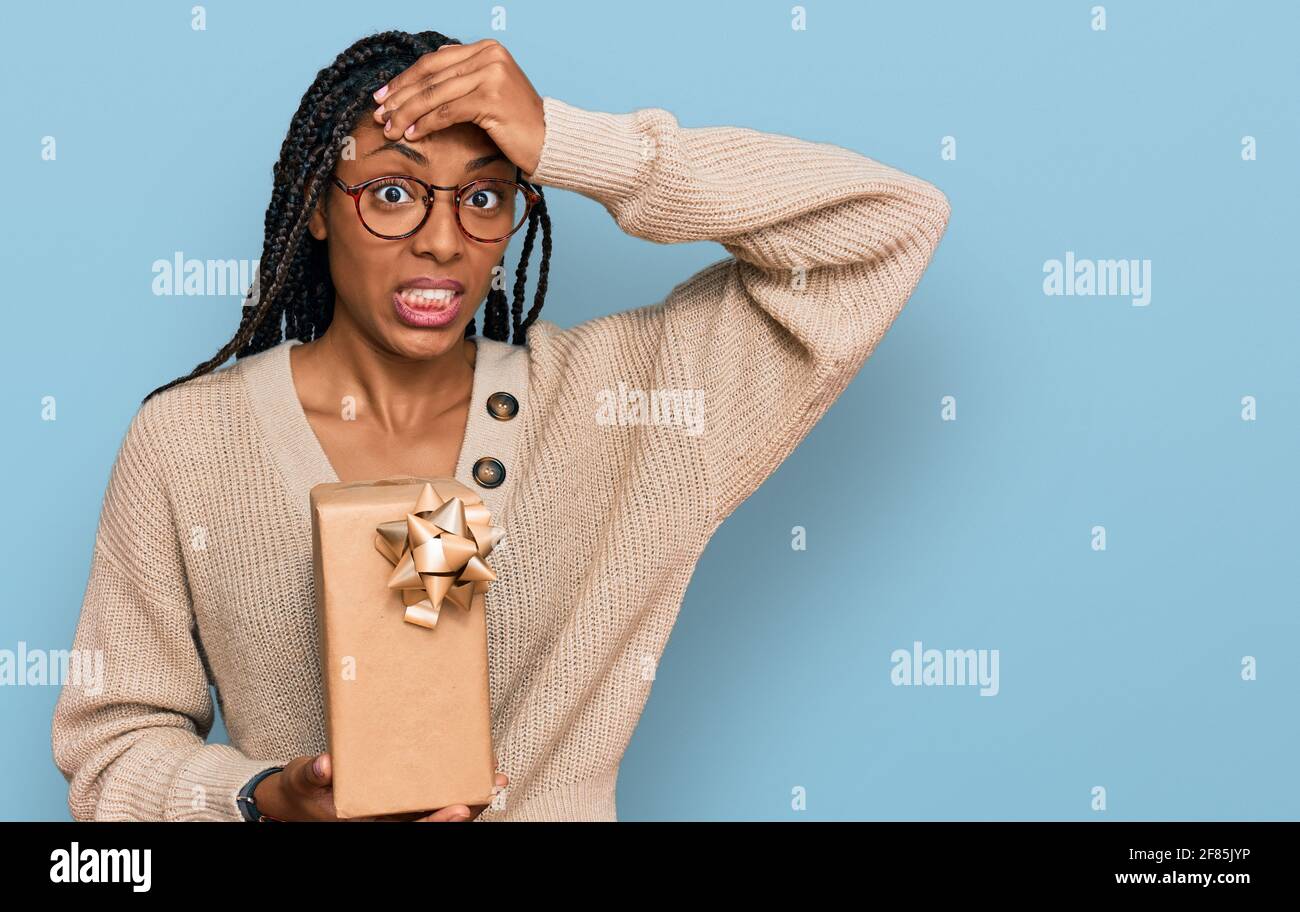 African american woman holding gift stressed and frustrated with hand ...