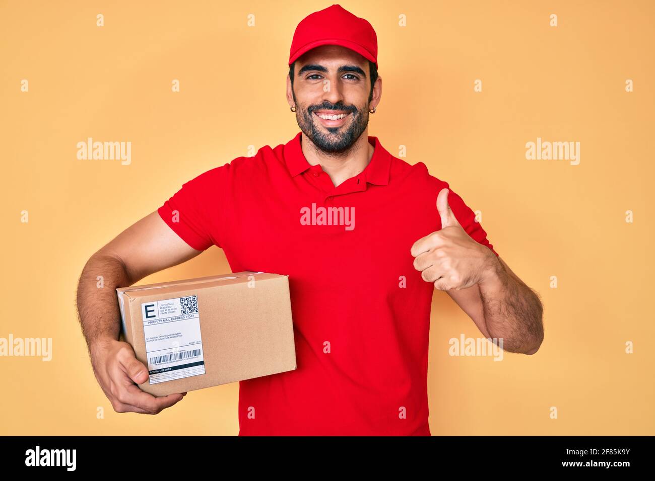 Handsome hispanic man with beard holding delivery package smiling happy ...