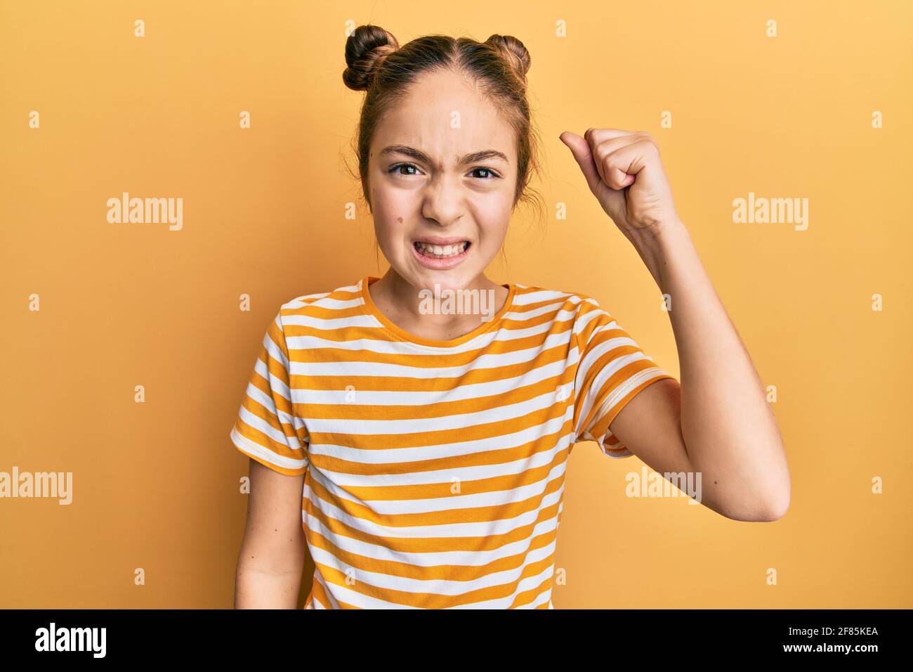 Beautiful brunette little girl wearing casual striped t shirt angry and ...
