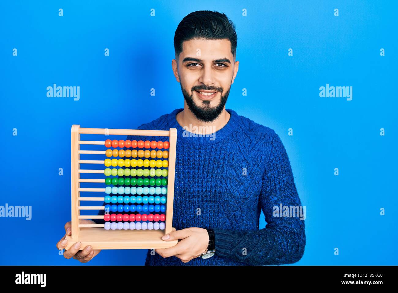 Handsome man with beard holding traditional abacus looking positive and ...