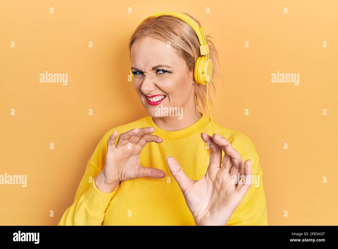 Young blonde woman listening to music using headphones disgusted ...