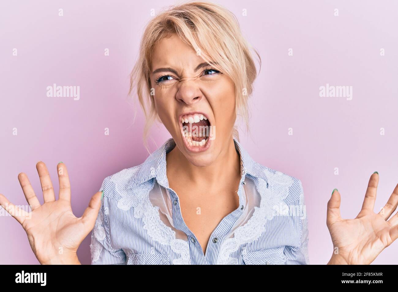 Young blonde girl wearing casual clothes crazy and mad shouting and ...