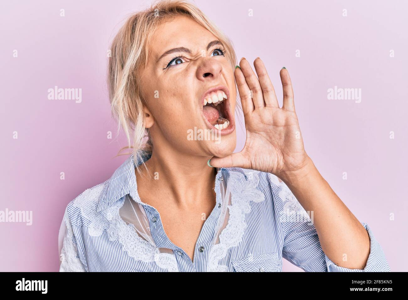 Young blonde girl wearing casual clothes shouting and screaming loud to ...