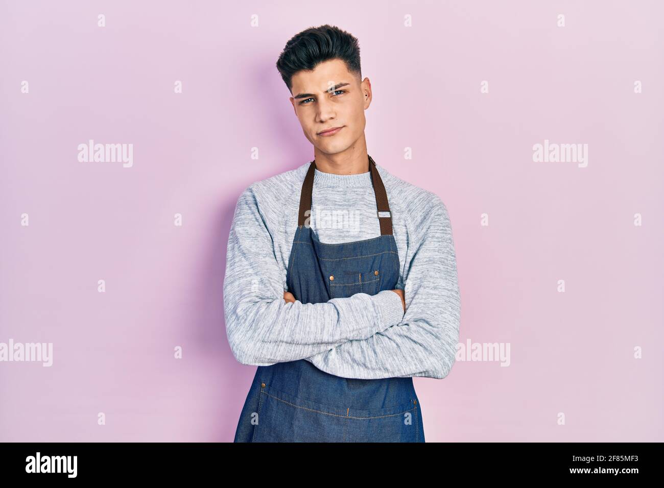 Young hispanic man wearing apron skeptic and nervous, disapproving ...