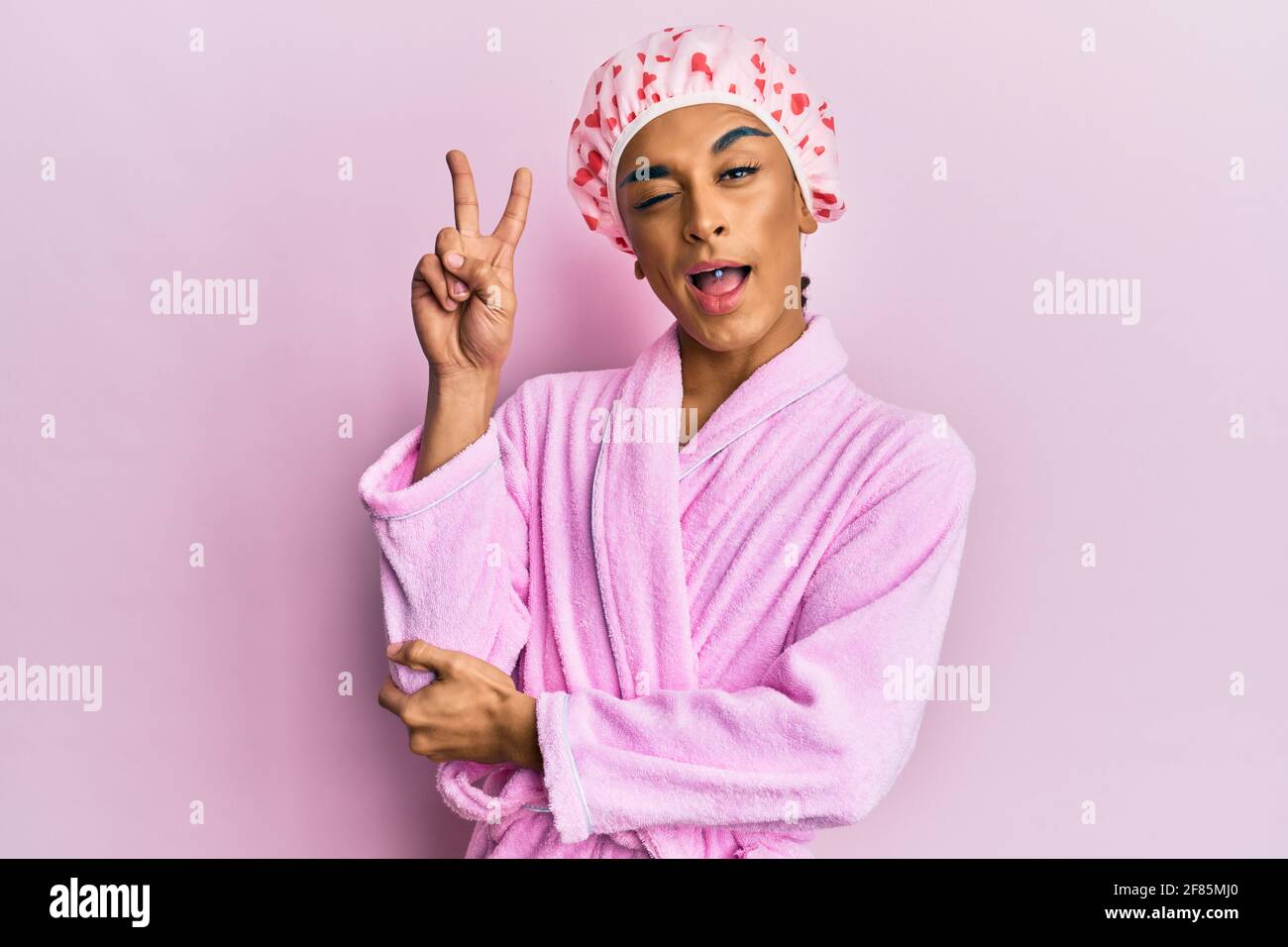 Hispanic man wearing make up wearing shower towel cap and bathrobe ...