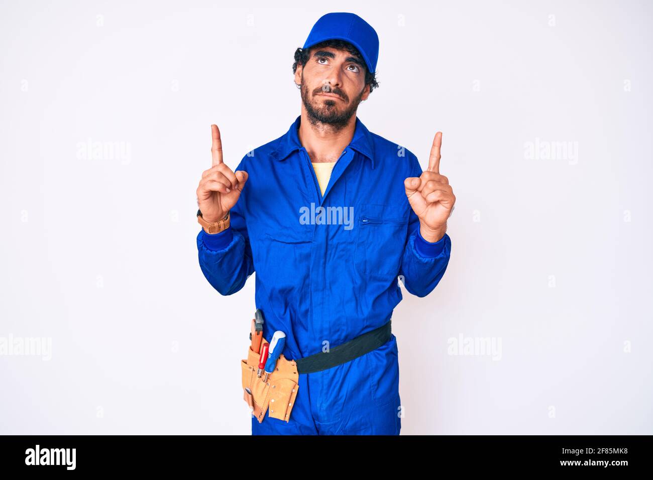 Handsome young man with curly hair and bear weaing handyman uniform ...