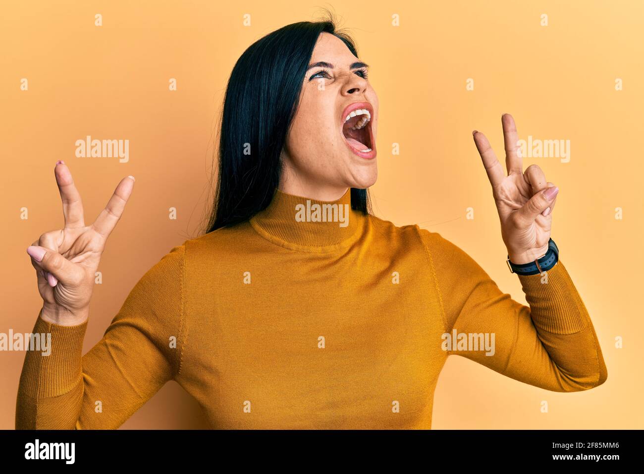 Young caucasian woman doing victory sign positive gesture angry and mad ...