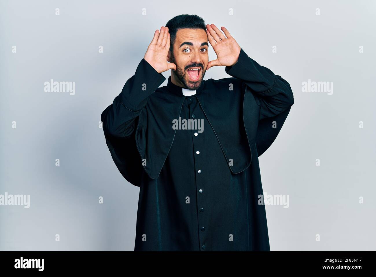 Handsome hispanic man with beard wearing catholic priest robe smiling ...