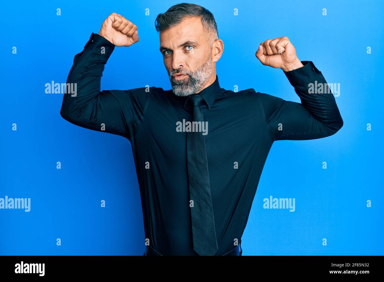 Middle age handsome man wearing business shirt and tie showing arms ...