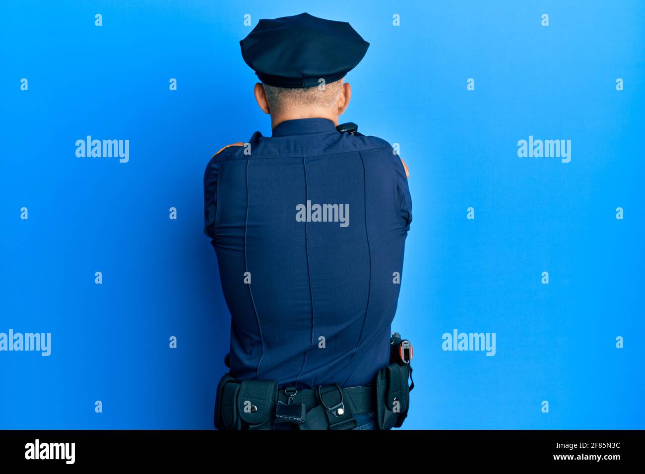 Middle age handsome man wearing police uniform hugging oneself happy ...