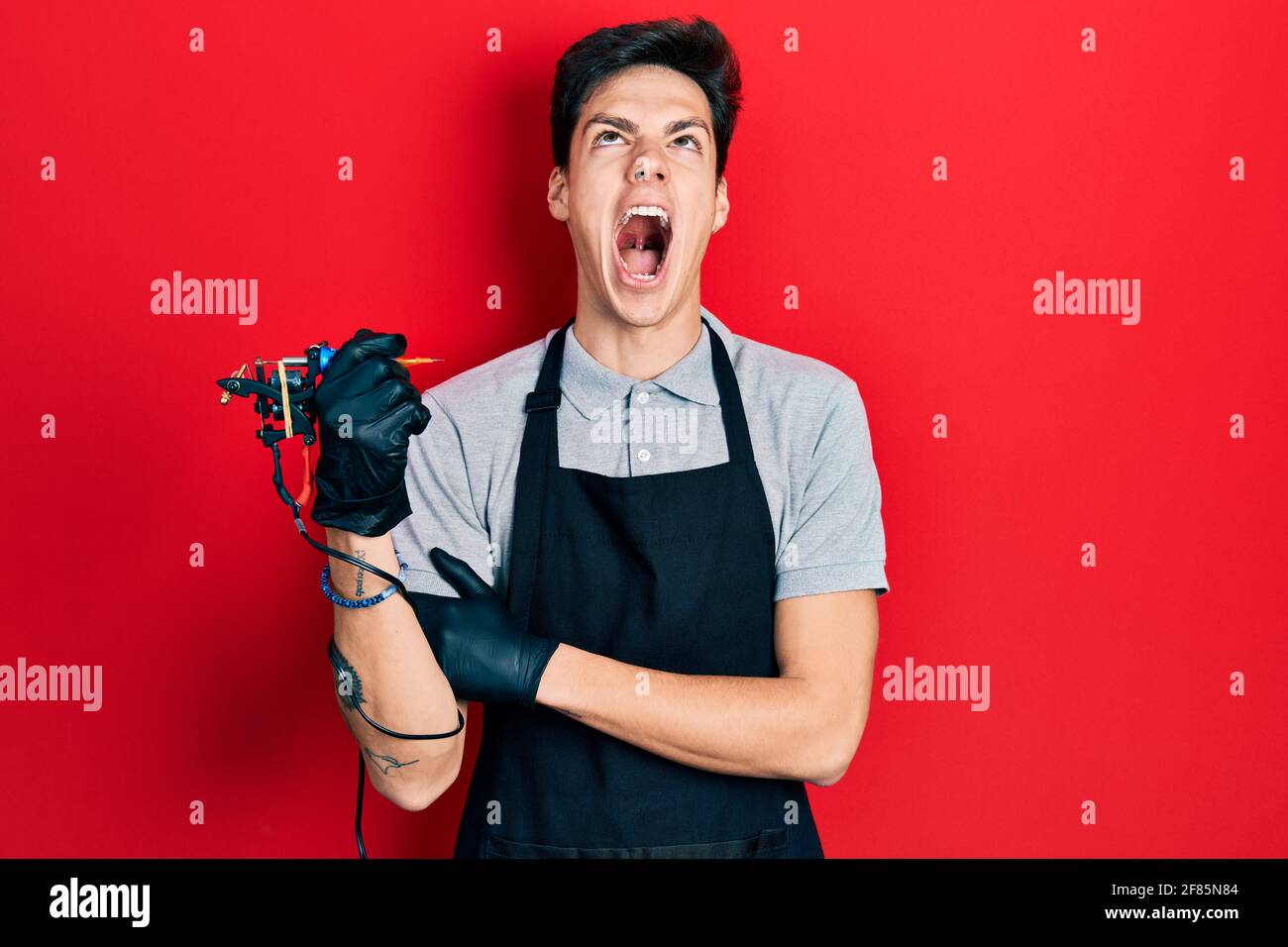 Young hispanic man tattoo artist wearing professional uniform and ...