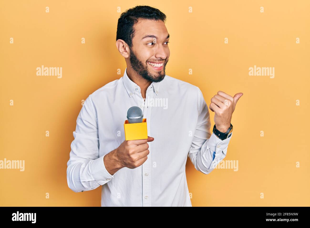 Hispanic man with beard holding reporter microphone pointing thumb up ...
