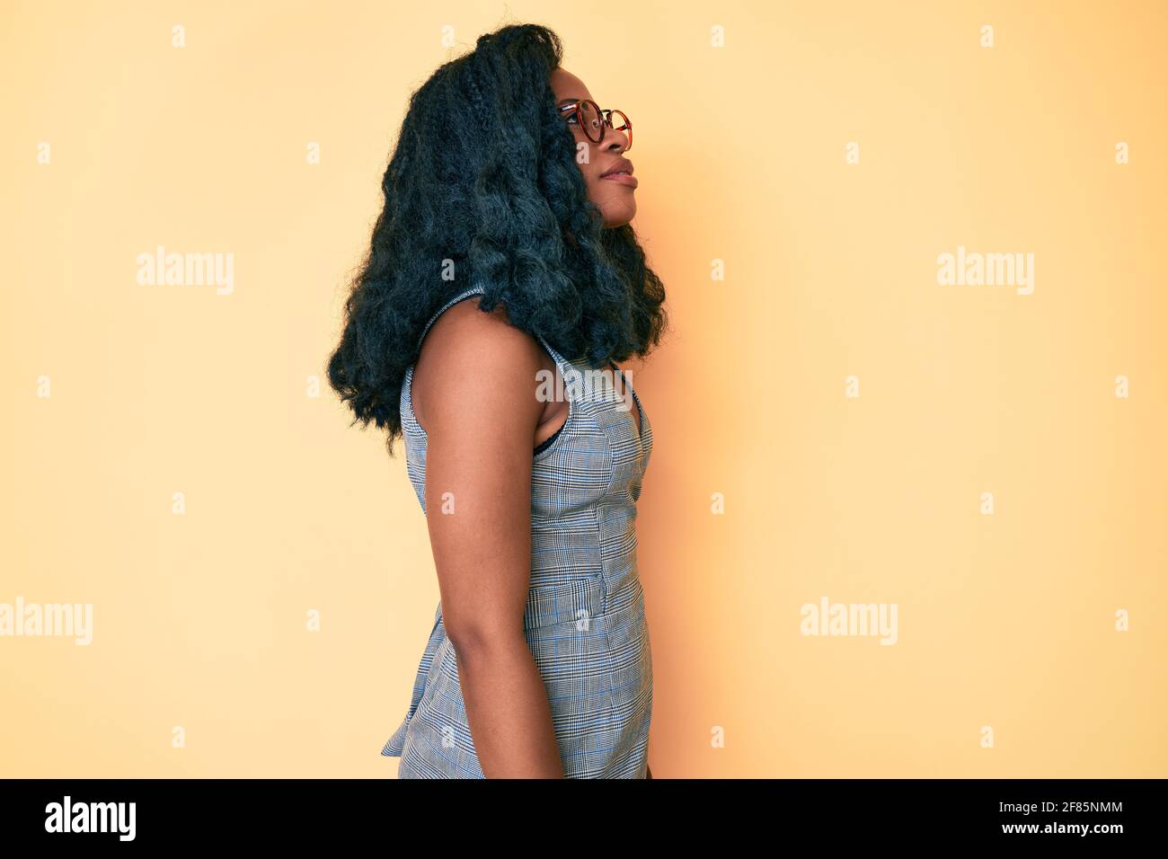 Beautiful african woman wearing business dress and glasses looking to ...