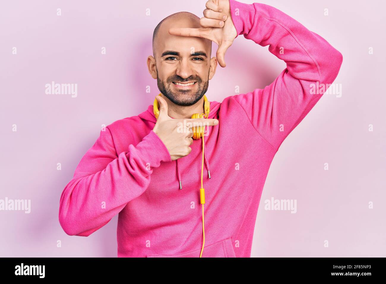 Young bald man wearing gym clothes and using headphones smiling making ...