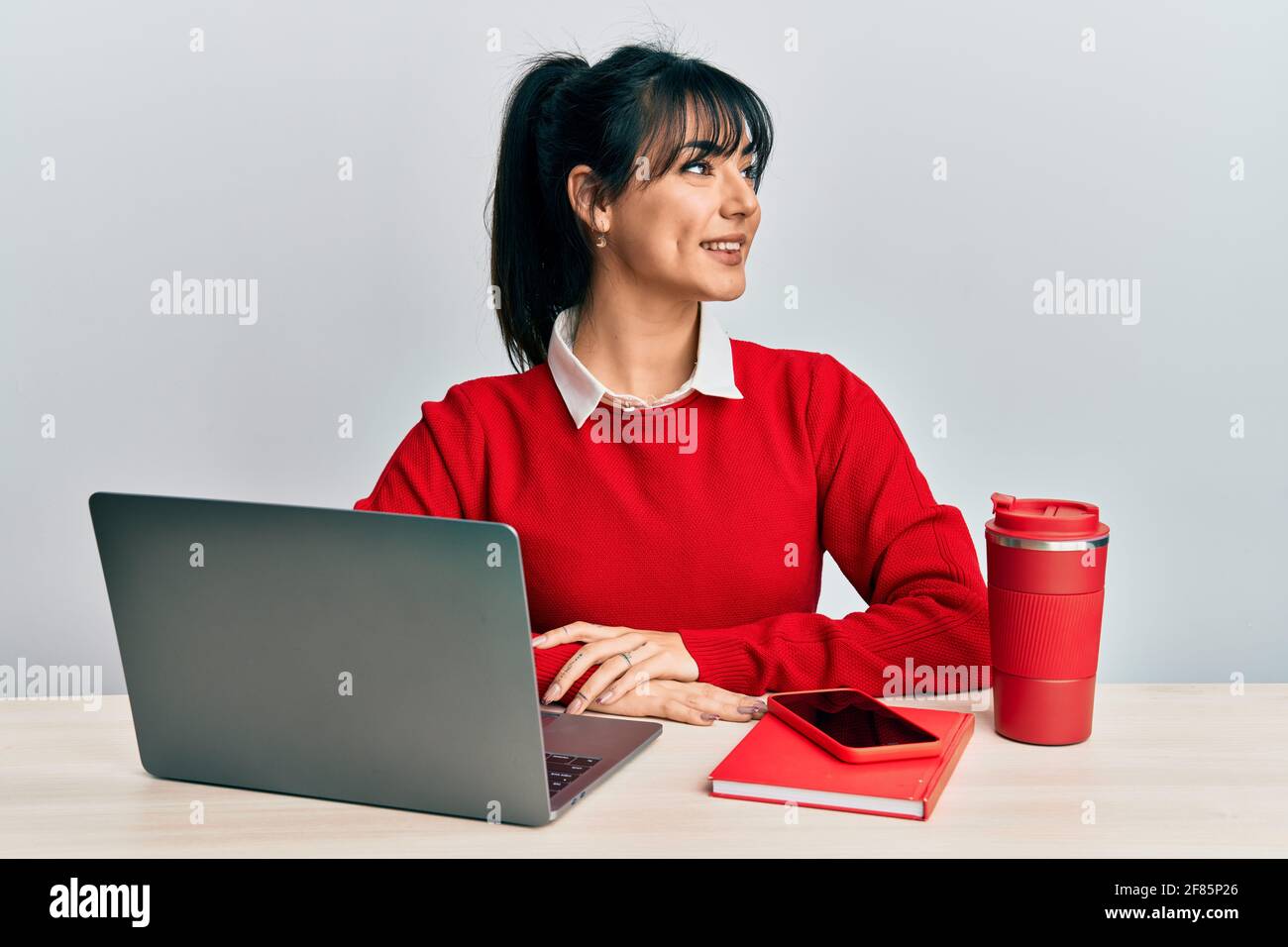 Young brunette woman with bangs working at the office with laptop ...