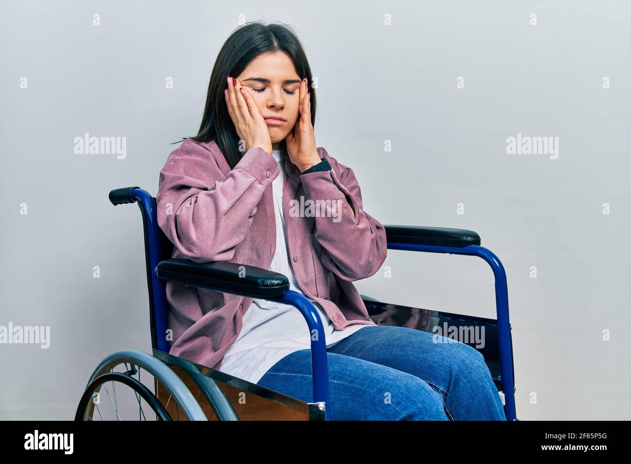 Young brunette woman sitting on wheelchair tired hands covering face ...