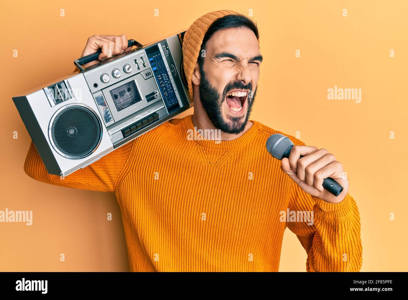 Young hispanic man holding boombox, listening to music singing with ...