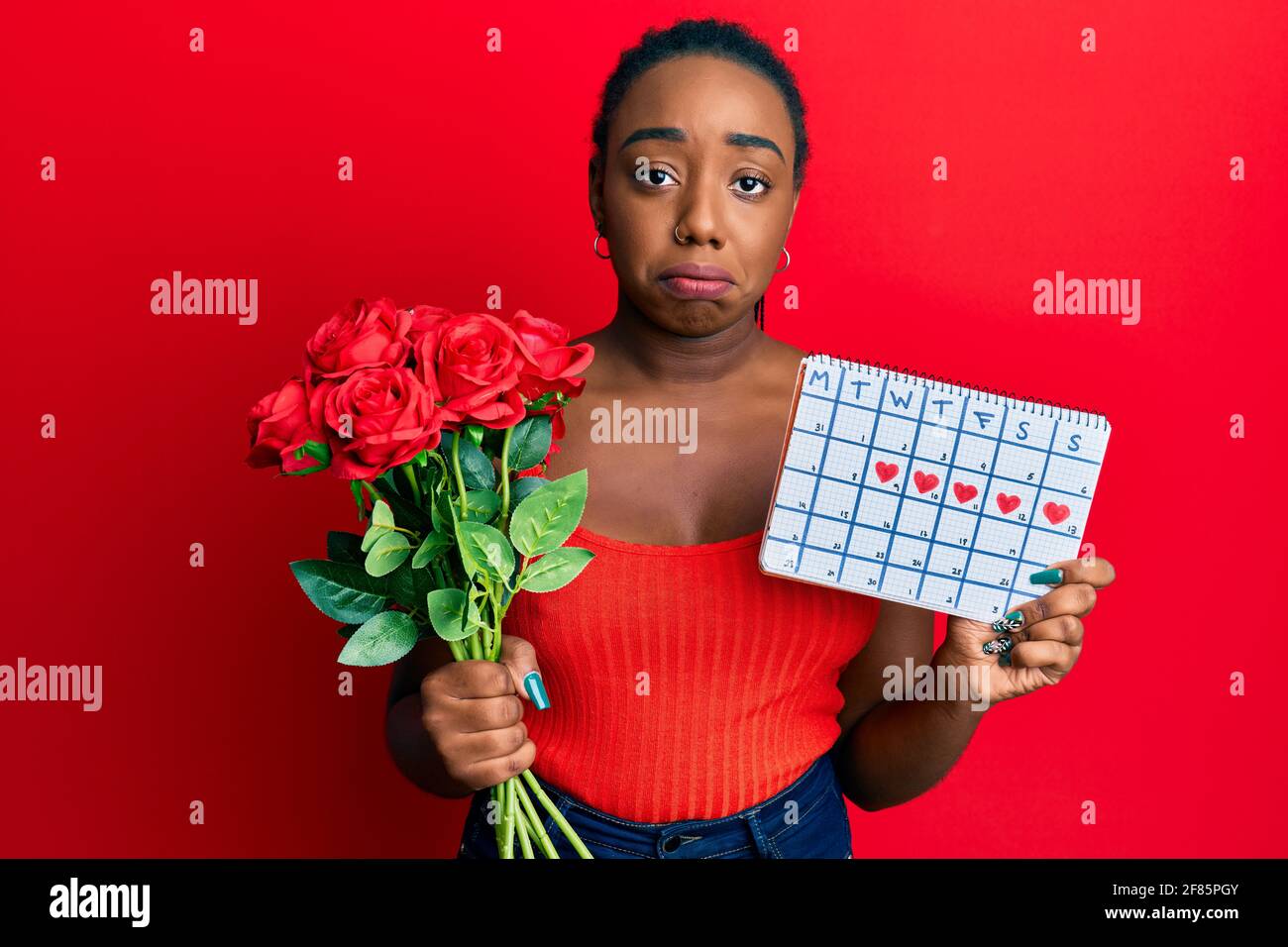 Young african american woman holding heart calendar and flowers ...