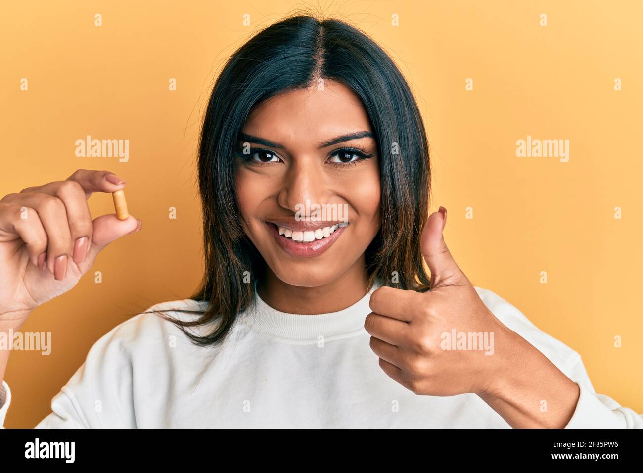 Young latin transsexual transgender woman holding pill smiling happy ...