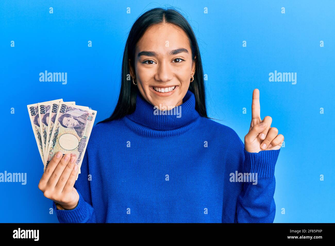 Young asian woman holding 5000 japanese yen banknotes smiling with an ...