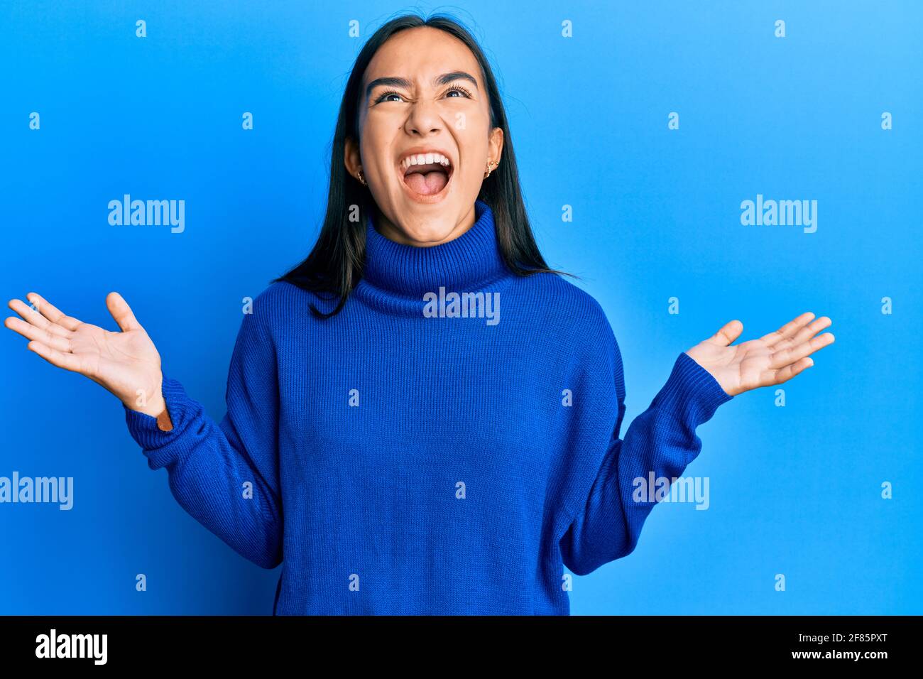 Young asian woman wearing casual winter sweater crazy and mad shouting ...